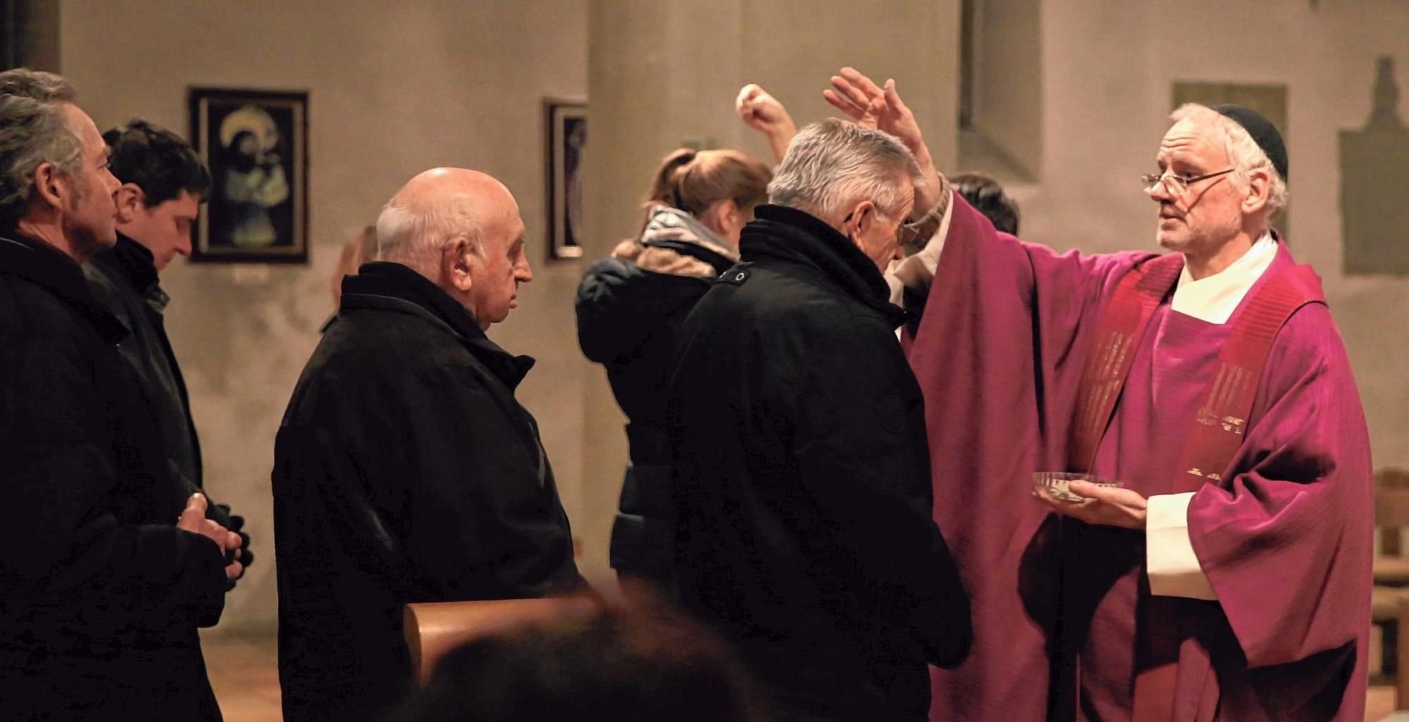 Pfarrer Bernhard Staudacher streut Gläubigen Asche auf ihr Haupt
